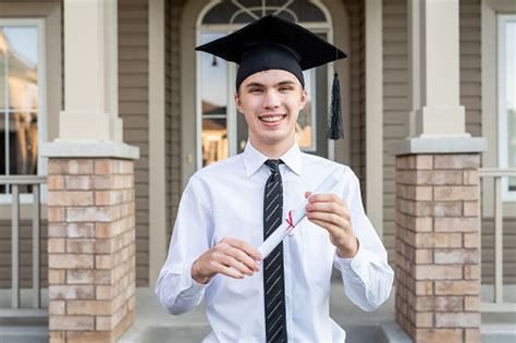 집 앞에서 졸업 모자를 쓰고 졸업장을 들고 있는 젊은 남성 학생 고등학교에 대한 스톡 사진 및 기타 이미지 고등학교 교외 교육 Istock
