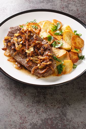 Zwiebelrostbraten은 양파와 튀긴 감자를 곁들인 독일 스테이크 Bratkartoffeln 클로즈업을 접시에 올려 놓습니다 세로 갈색에 대한 스톡 사진 및 기타