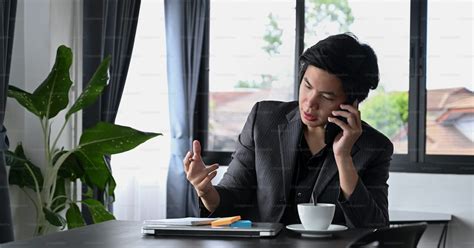 그의 비즈니스 파트너와 휴대 전화로 이야기하는 진지한 사업가 사진 Unsplash의 태국 이미지