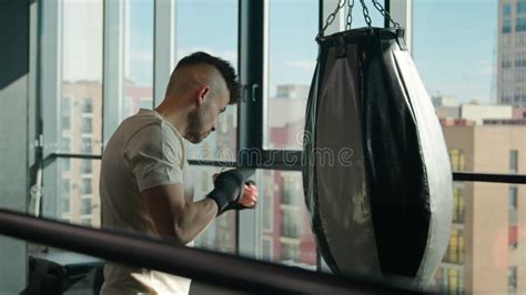 Tired Athlete Training Boxing With Punching Bag In Modern Fitness Gym