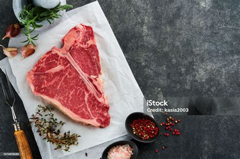 두꺼운 생 티본 스테이크 드라이 에이징 생 티본 또는 포터하우스 쇠고기 고기 양피지에 스테이크어두운 배경에 허브와 소금이 있습니다 평면도 및 복사 공간 티본 스테이크에 대한