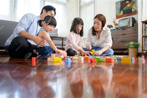 Азиатская семья с детьми играющими и строящими башню из красочных деревянных игрушечных блоков