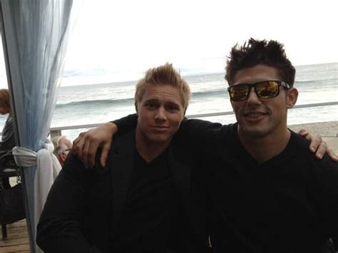Two Men Sitting Next To Each Other Near The Ocean