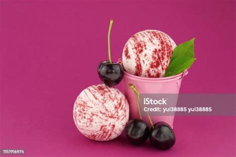 달콤한 체리 추출 물과 목욕 폭탄 분홍색 장식 양동이 밝은 분홍색 배경에 잘 익은 체리 열매에서 세트 목욕을 위한 둥근 줄무늬 폭탄 유기농 베리 바디 코스메틱 개체 그룹에