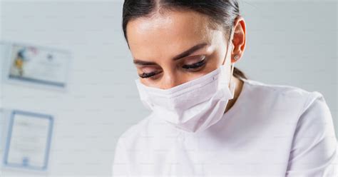 얼굴 마스크를 쓴 검은 머리의 젊은 여성 피부과 의사가 스트레치 마크에 대한 메조 테라피 절차를 수행합니다 사진 Unsplash의 피부과 이미지