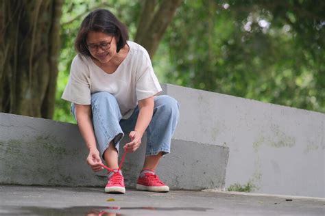 Premium Photo Asian Woman Sitting Alone In The Park Fixing Her Shoe Lace After A Long Walk