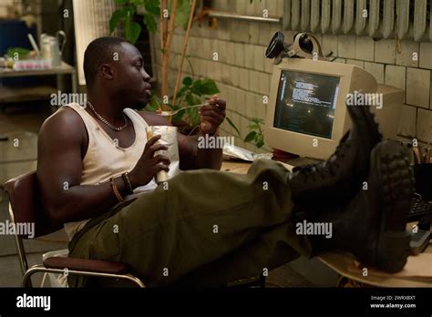 Young Black Male Programmer Sitting At Workplace Looking At Code On Old