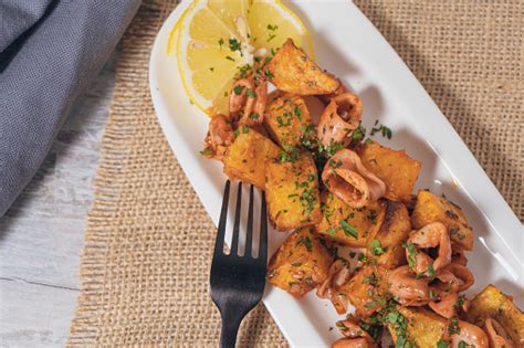 마늘과 감자를 곁들인 아기 오징어인 식페리티프 또는 전형적인 스페인 타파는 레몬과 포크가 달린 길쭉한 흰색 트레이에 소박한 배경을 가지고 있습니다 전통적인 음식 개념 0명에