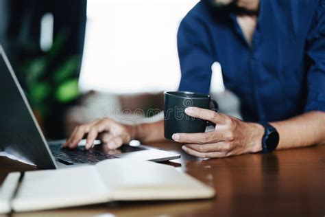 Portrait Of An Asian Man Working On A Computer And Drinking Coffee