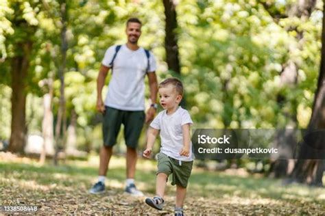 숲속의 산책 한 소년이 숲에서 놀고 풀밭을 걷고 있었고 아버지는 배경에서 그를 지켜보고 있습니다 행복한 어린 시절과 자연속에서 자라며 자연 속에서 놀아보며 2명에 대한 스톡