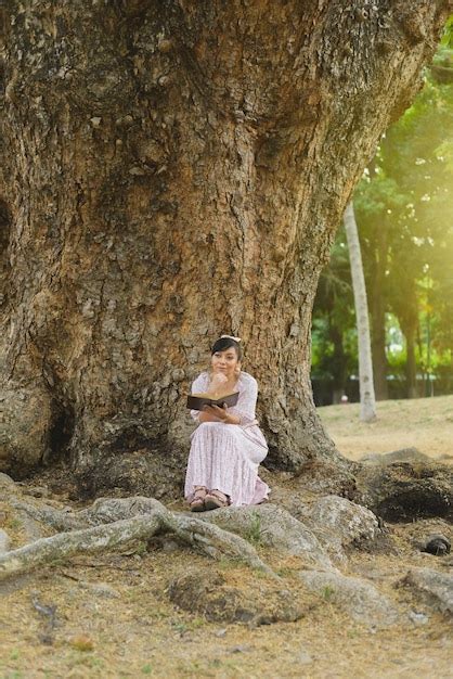 Premium Photo Woman Seated Next To A Tree Trunk In A Park Reading A Book World Book Day