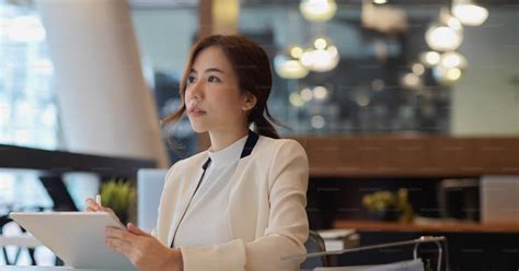 공식적인 정장을 입은 젊은 사업가의 초상화는 디지털 태블릿으로 작업하고 현대적인 사무실에서 그녀의 작업에 대해 고려하고 있습니다 소프트 포커스 사진 Unsplash의