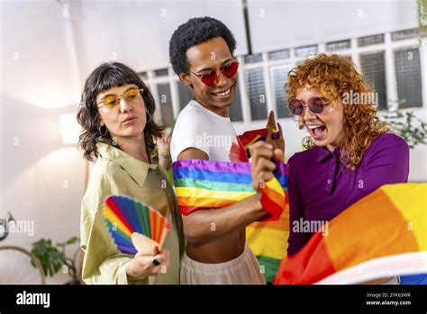 Happy Non Binary People Dancing With Rainbow Flag Partying At Home