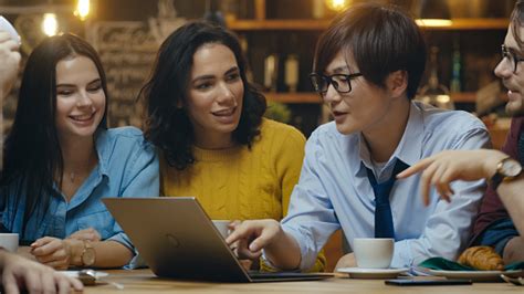 동료의 다양 한 그룹은 비즈니스 런치 바 레스토랑 그들은 문제 해결에 생각 하 고 랩톱 컴퓨터를 사용 하 여 세련 된 설립에 있는 아름 다운 젊은 사람들 계획에 대한 스톡