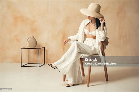 질감이 있는 복사 공간 벽이 있는 배경에 앉아 있는 모자를 쓴 의자에 있는 알아볼 수 없는 고급스러운 여성 해변에 대한 스톡 사진 및 기타 이미지 Istock
