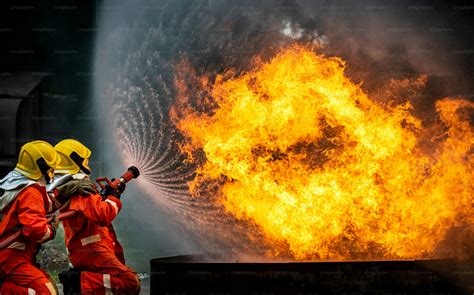 Two Firefighter Teamwork In Fire Suit With Fire Fighting Equipment