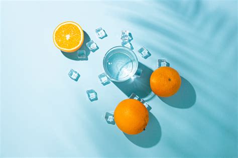 파란색 배경에 야자수 잎의 그림자 위에서 오렌지 물과 얼음 조각의 유리 상단 보기 플랫 레이 0명에 대한 스톡 사진 및 기타 이미지 Istock