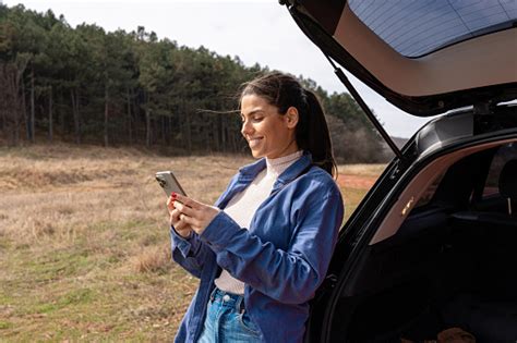 휴대 전화를 사용하는 젊은 백인 여성 트렁크가 열린 차에 기대어 25 29세에 대한 스톡 사진 및 기타 이미지 25 29세 Brand Name Online