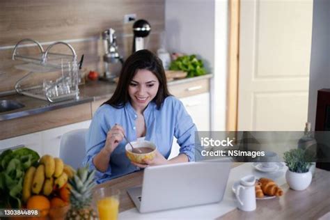 아침에 아침 식사 테이블에 앉아있는 동안 노트북에서 일하는 아름다운 젊은 여성 스톡 사진 20 29세에 대한 스톡 사진 및 기타 이미지 20 29세 가정 생활 가정