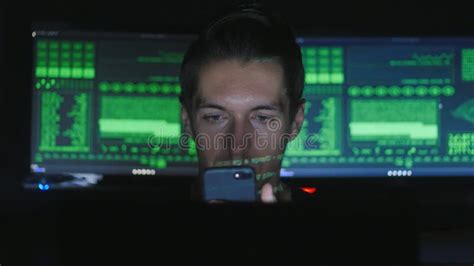 Hacker Programmer Uses A Smartphone While Green Code Characters Reflect