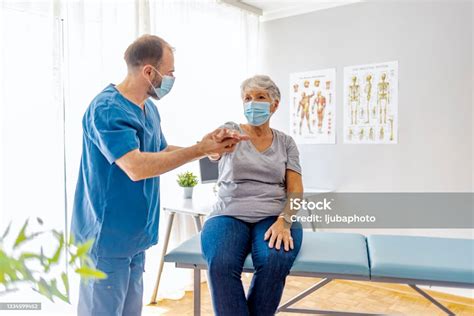 스트레칭 운동을 하는 환자를 돕는 보호 얼굴 마스크를 가진 치료사 2명에 대한 스톡 사진 및 기타 이미지 2명 40 49세 45 49세 Istock