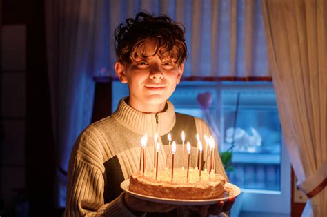생일을 축하하는 사랑스럽고 행복한 금발 십대 소년 집에서 구운 케이크에 촛불을 불고 있는 십대 아이 실내 학교 어린이의 생일 파티 자축 청소년 생일 고등학교 이하에 대한