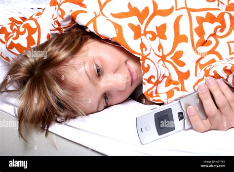 Young Woman Lying In Bed Under A Vibrant Orange Patterned Blanket