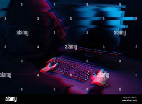 Hacker In The Hood Working With Computer Typing Text In Dark Room Image With Glitch Effect