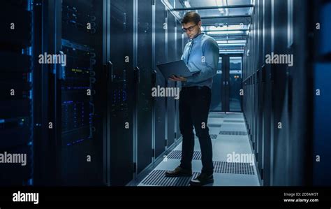 In Data Center It Engineer Stands Before Working Server Rack Doing
