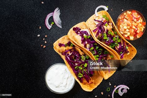 닭고기 구운 채소 양파 보라색 양배추를 곁들인 전통 멕시코 타코와 흰색과 붉은 소스 양파 링이 함께 나옵니다 맨 위 보기 어두운