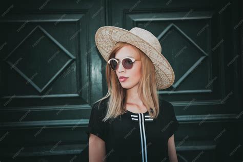 Premium Photo Woman In Sunglasses And Hat Standing Against Door