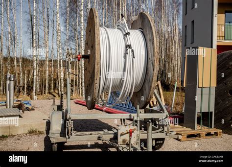 Huge Industrial Wooden Cable Spool With Coiled White Cable On A Mobile