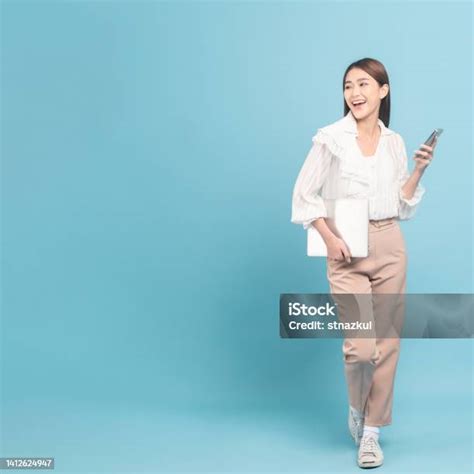 스마트 캐주얼 천을 입은 젊은 아름다운 아시아 여성 스마트 폰을 사용하여 파란색 배경에 고립 된 복사 공간을 봅니다 캐쥬얼 의류에 대한 스톡 사진 및 기타 이미지 Istock