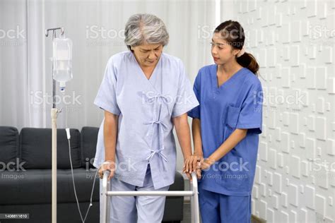 요양원의 젊은 아시아 간호사는 장애인 노인 여성을 돌봅니다 간병인 의사는 노인 환자가 운동을하고 보행기 또는 지팡이를 걷는 연습을 할 수 있도록 물리 치료를 제공합니다