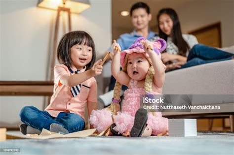 동생은 여동생과 놀고 있었습니다 그는 손을 들어 집 거실에 있는 양탄자에 있는 여동생을 바라보며 웃었고 부모님은 소파에 앉아 멀리 서 있는 것을 보았습니다 가정 개념의 가족