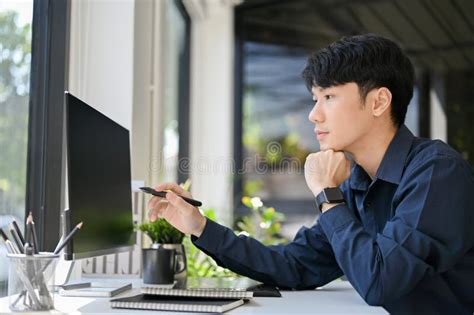 Smart Asian Male Office Worker Or Businessman Focusing On His Task Looking At Computer Screen
