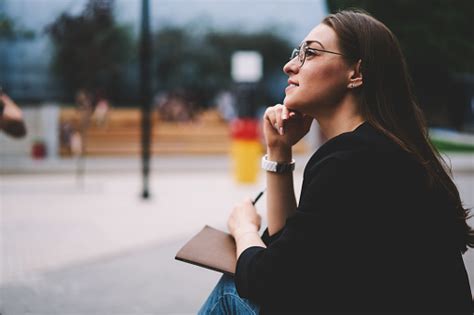 야외에서 휴식을 취하며 대학 말에 대해 생각하고 도시 설정에 메모장에 앉아있는 동안 꿈꾸는 여성 교과서에서 숙제를 한 후 숙고하는 긍정적 인 여성 20 대 교과서에 대한