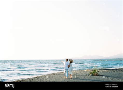 Man Shows The Sea With His Finger To The Woman Standing On The Beach