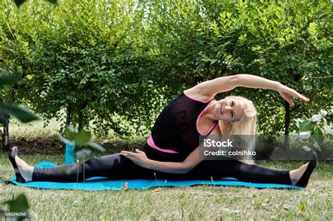 긍정적 인 금발 의 여자는 공원에서 스트레칭 운동을 수행합니다 피트니스 야외 운동 40 44세에 대한 스톡 사진 및 기타 이미지