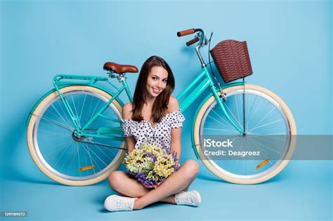 전체 길이의 사진 의 레이디 앉아 바닥 교차 다리 홀드 무리 꽃 자전거 착용 점선 드레스 신발 고립 된 블루 컬러 배경 두발자전거에 대한 스톡 사진 및 기타 이미지 Istock