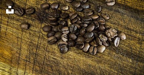 나무 테이블 위에 앉아 있는 커피 원두 더미 사진 Unsplash의 무료 커피 이미지