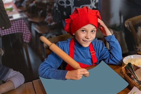 요리사의 형태로 웃는 소년 나무 롤링 핀을 들고 피자를 요리 할 준비를하고 있습니다 요리를위한 도구 및 장비 텍스트 모형을위한