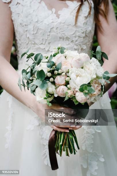하얀 드레스를 입고 신부 파스텔 핑크 흰 모란 장미 꽃 신 록의 아름 다운 웨딩 부케를 들고 고 녹지의 배경에 리본으로 장식 결혼식에 대한 스톡 사진 및 기타 이미지