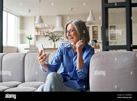 Une vieille femme mûre et excitée qui lit un message sur son smartphone