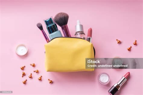 분홍색 배경에 고립 된 화장품과 브러시로 가방을 구성하십시오 화장품이 있는 옐로우 백 기본 색상 핑크와 골드 스킨 크림 립스틱