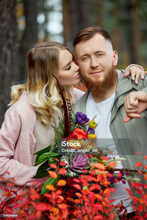 사랑에 부부는 가을 숲을 통해 산책 포옹과 남자와 여자의 키스 관계와 사랑 젊은 부부는 노란색 빨간 잔디에 서 소녀 손에 꽃다발 2명에 대한 스톡 사진 및 기타 이미지