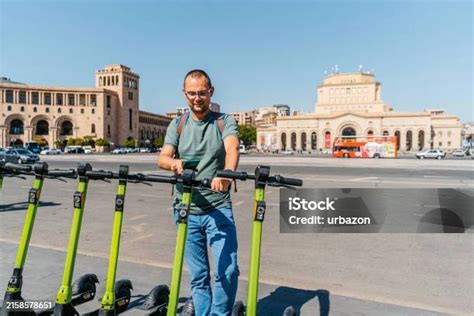 아르메니아 예레반의 공화국 광장에서 스마트 폰을 사용하여 전기 스쿠터를 임대하는 중년 남성 Brand Name Mobile Payment에 대한 스톡 사진 및 기타 이미지