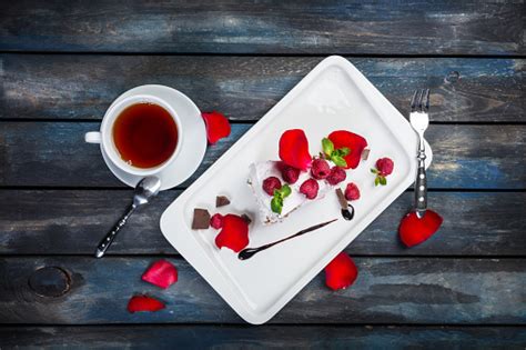 차 한잔과 함께 맛 있는 파블로 케이크입니다 장미 꽃잎과 흰색 접시에 신선한 나무 딸기 최고의 볼 수 있습니다 아름 다운 나무 배경입니다 딸기에 대한 스톡 사진 및 기타