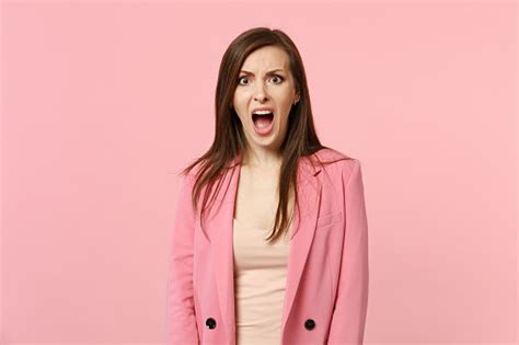 스튜디오에서 파스텔 핑크 배경에 고립 된 카메라 비명과 맹세를 보이는 재킷을 입고 충격 성 난 젊은 여자의 초상화 사람들은 진심으로 감정 라이프 스타일 개념입니다 복사
