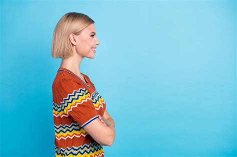 밥 머리를 가진 소녀 같은 유쾌한 여자의 옆 프로필 사진 팔짱을 끼고 로고를 보고 빈 공간을 파란색 배경에 고립 미소에 대한